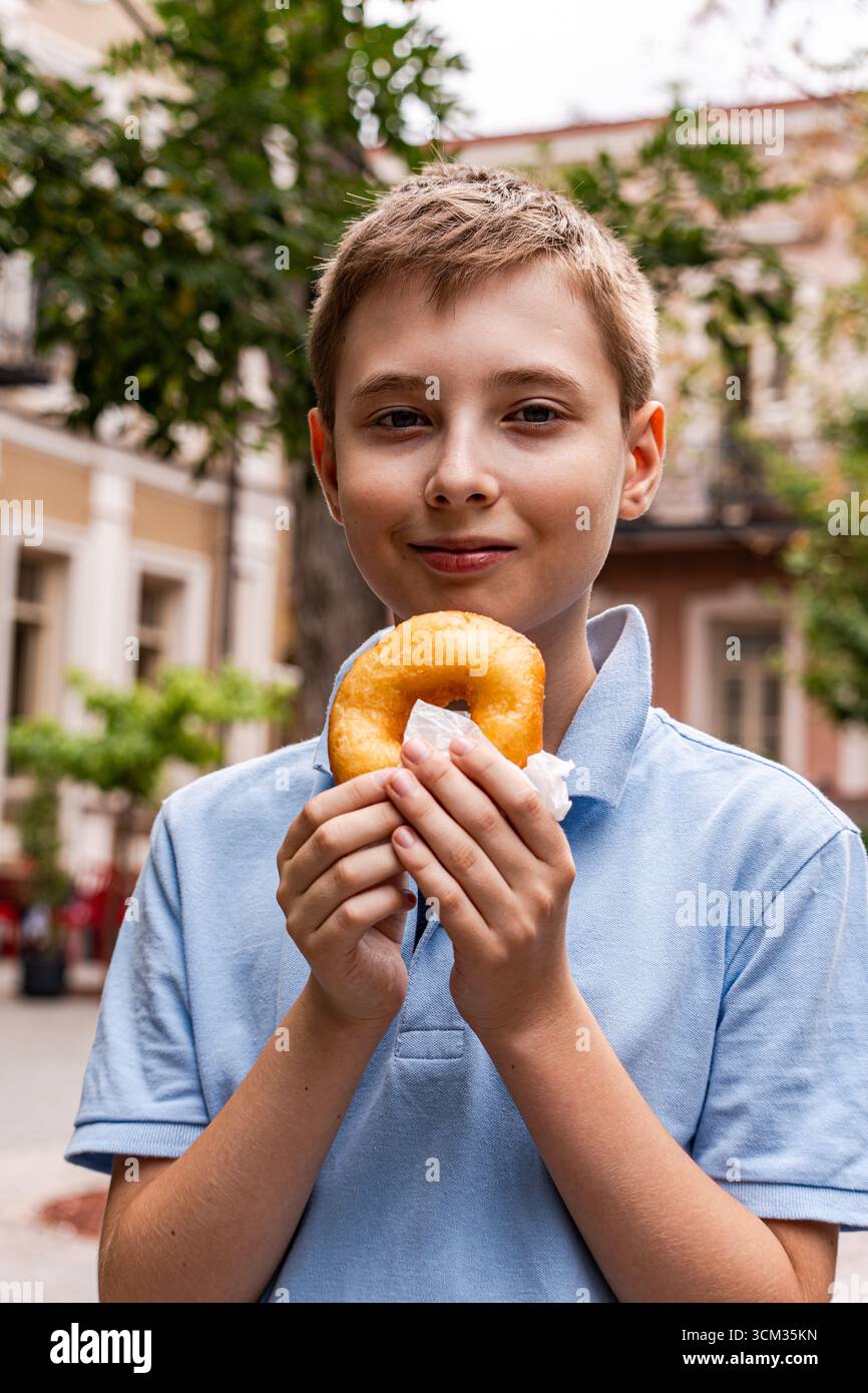 Traditional sugar donut in the hand of boy Stock Photo - Alamy