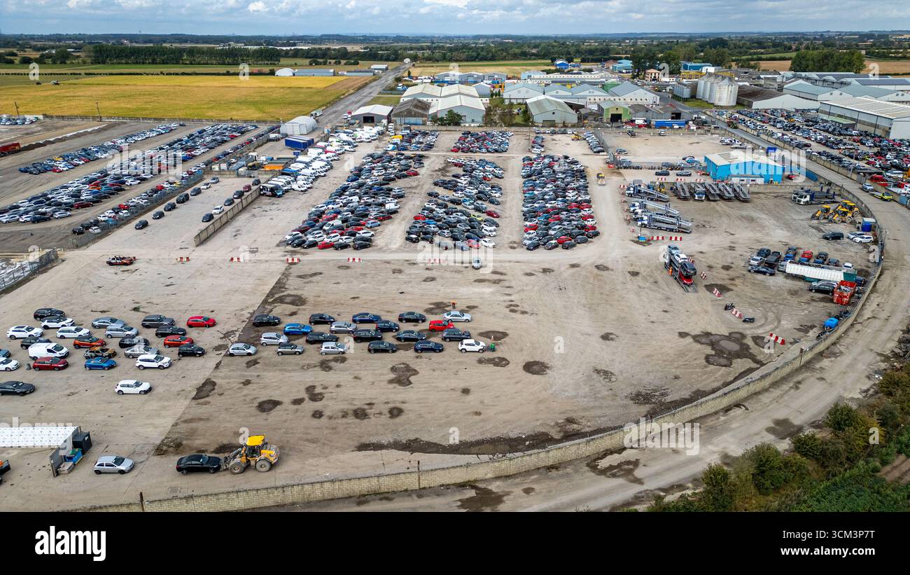 Aerial view of a vast vehicle storage lot filled with cars, trucks, and ...