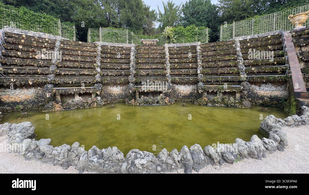 An ornate, tiered stone structure with a pond at its base, set against ...