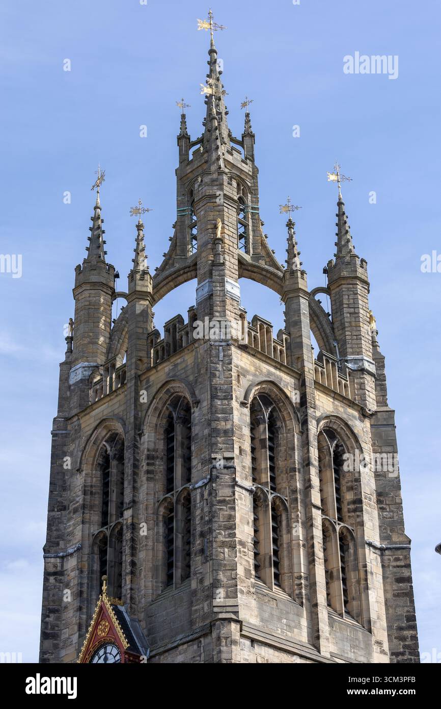 A stone church tower with arched windows and golden spires against a ...