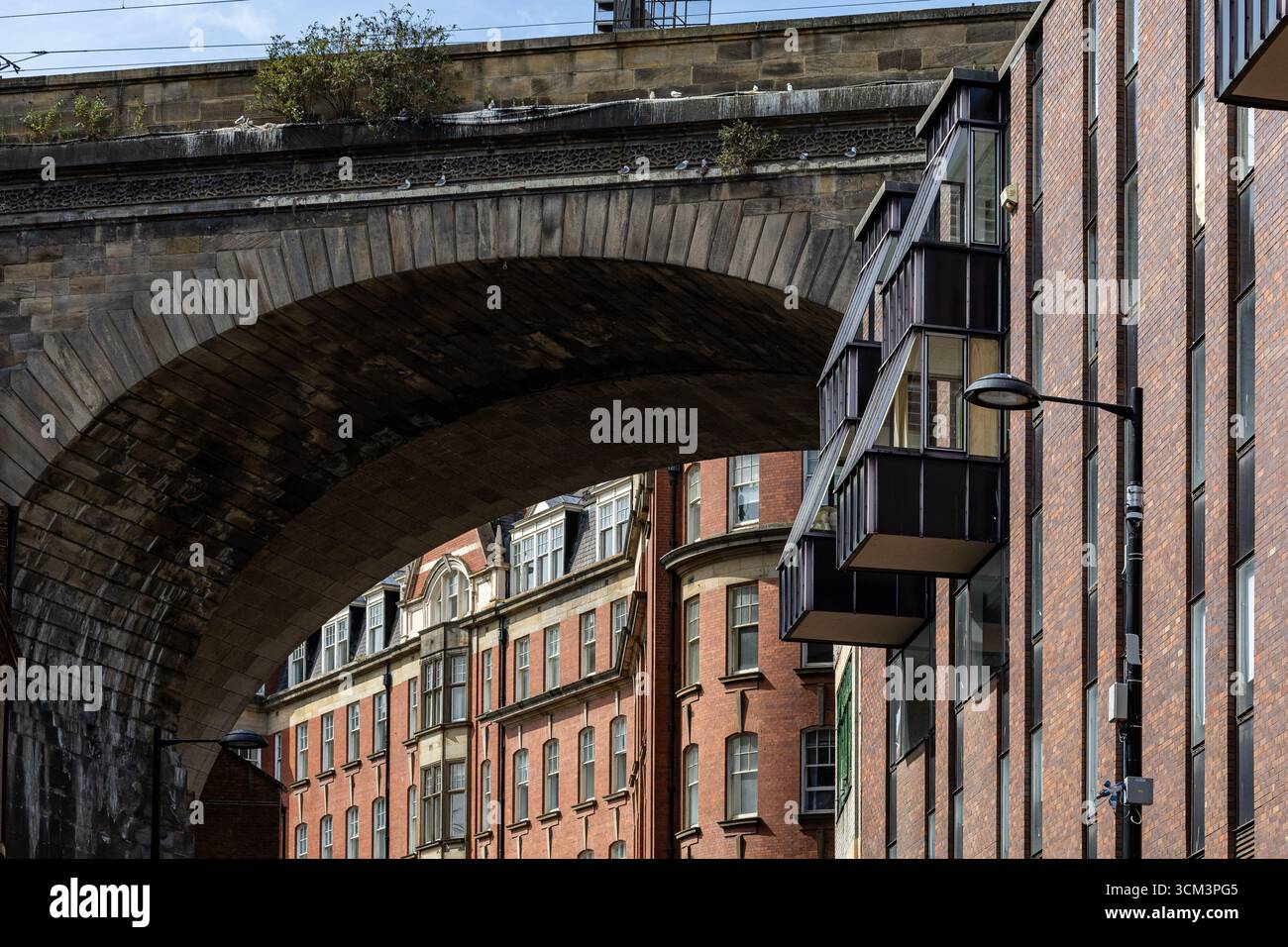 A stone railway arch frames a view of brick buildings with modern ...