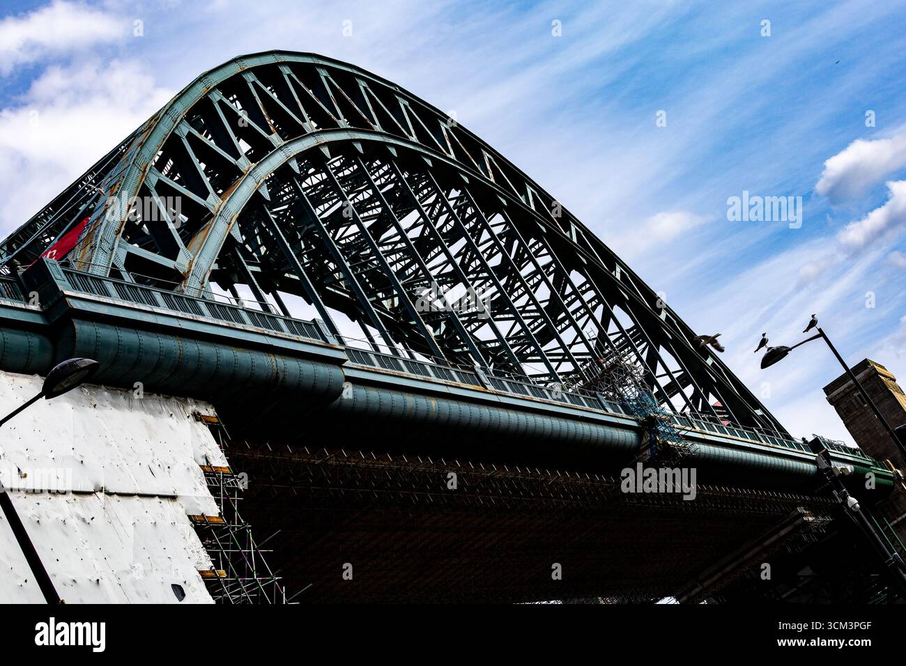 A low-angle view of a steel arch bridge with a complex lattice ...