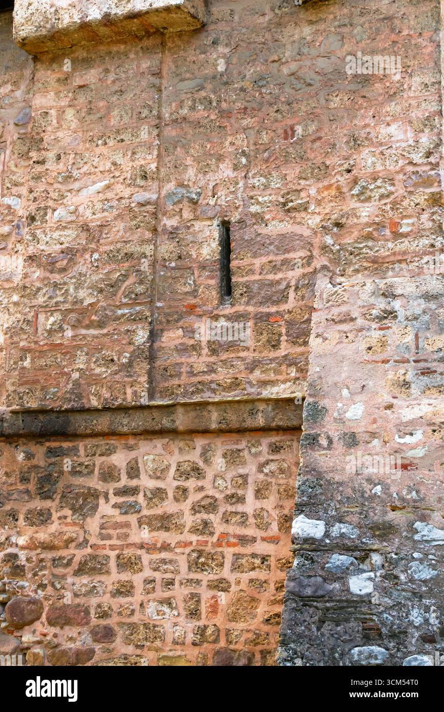 Close-up of an old medieval fortress wall showing a narrow slit window ...