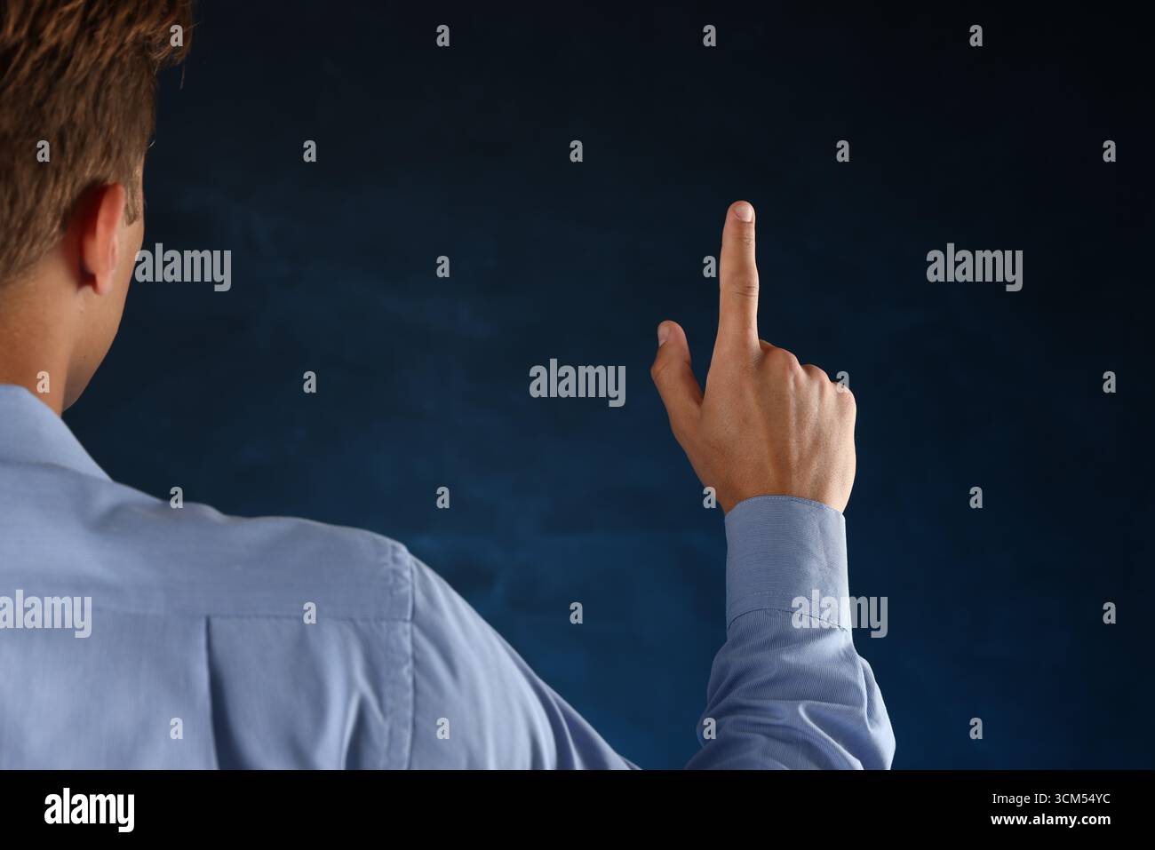 Man touching something on blue background, back view Stock Photo - Alamy