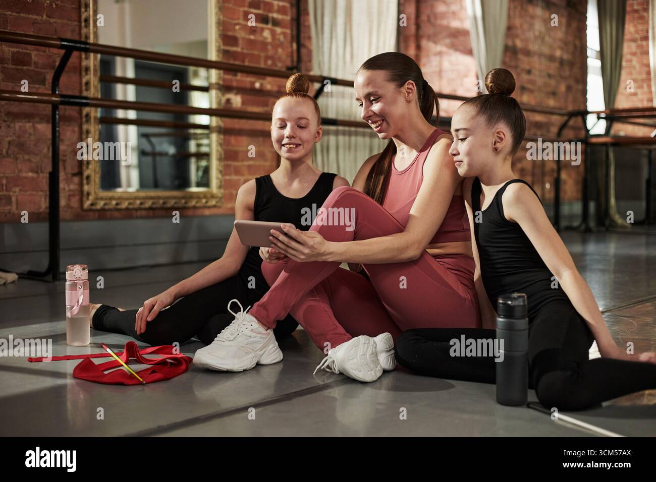 Caucasian female rhythmic gymnastics coach sitting on dance studio ...