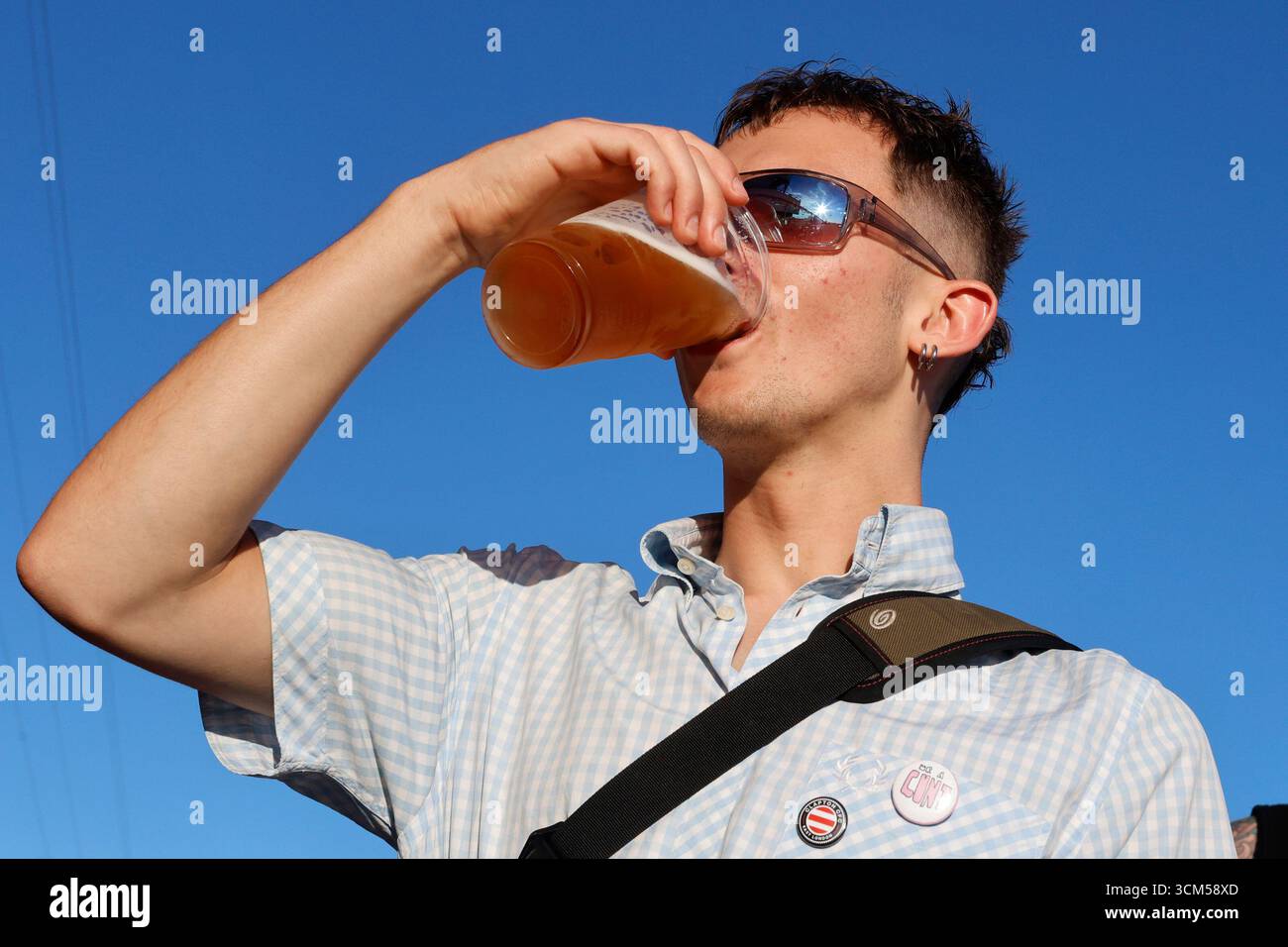 A young man drinking a pint of lager from a plastic cup Stock Photo - Alamy