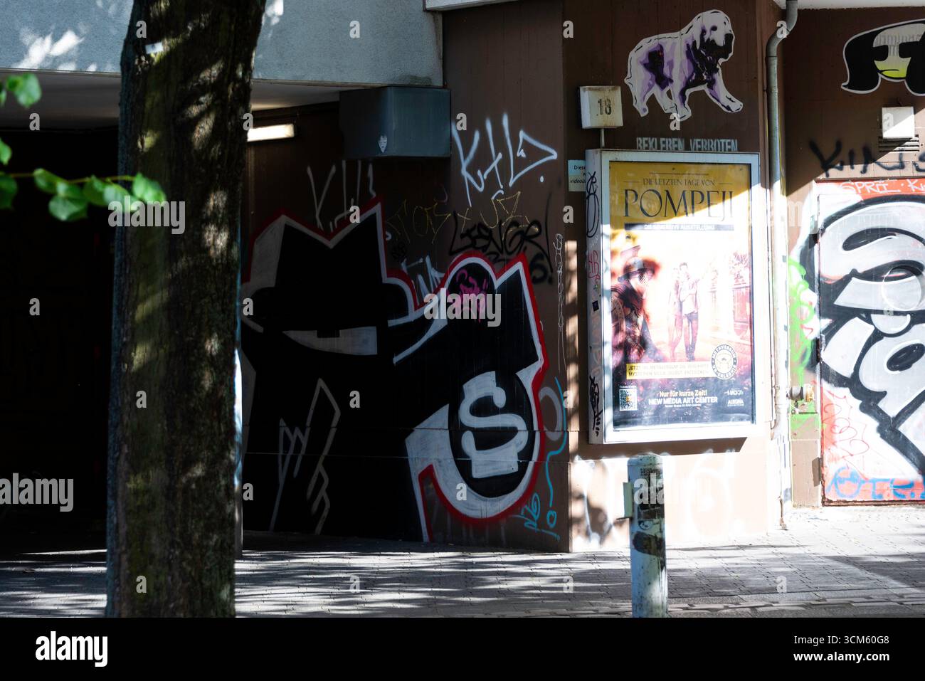 A sun-drenched street corner in Berlin's Kreuzberg. The wall is a ...