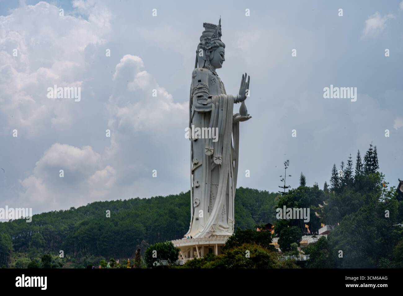 A large white statue of Quan Âm, the Buddhist Goddess of Mercy, stands ...