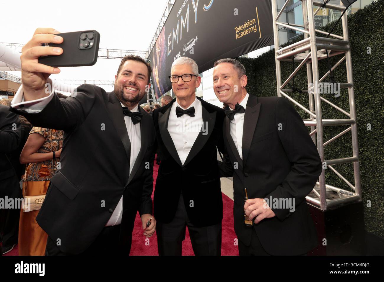 Tim Cook, center, walks the red carpet at the 77th Emmy Awards on ...