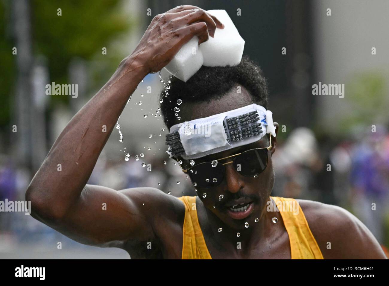 Sweden's athlete Suldan Hassan uses a soaked sponge to cool down as he ...