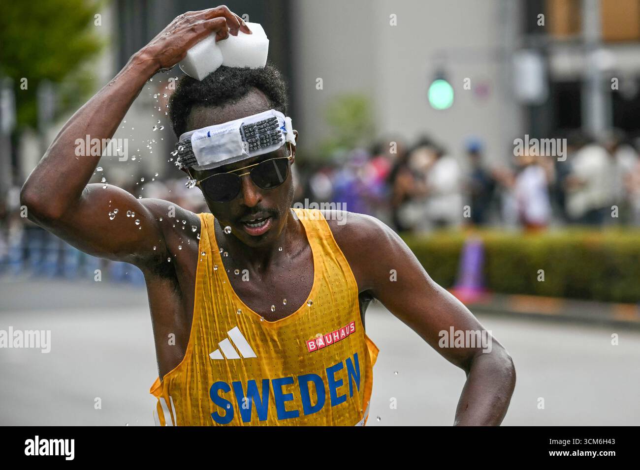 Sweden's athlete Suldan Hassan uses a soaked sponge to cool down as he ...