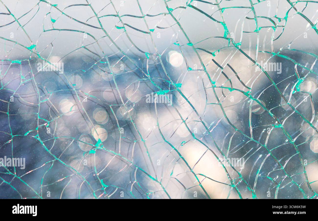 Sheet of shattered glass, surface covered in a network of sharp cracks ...