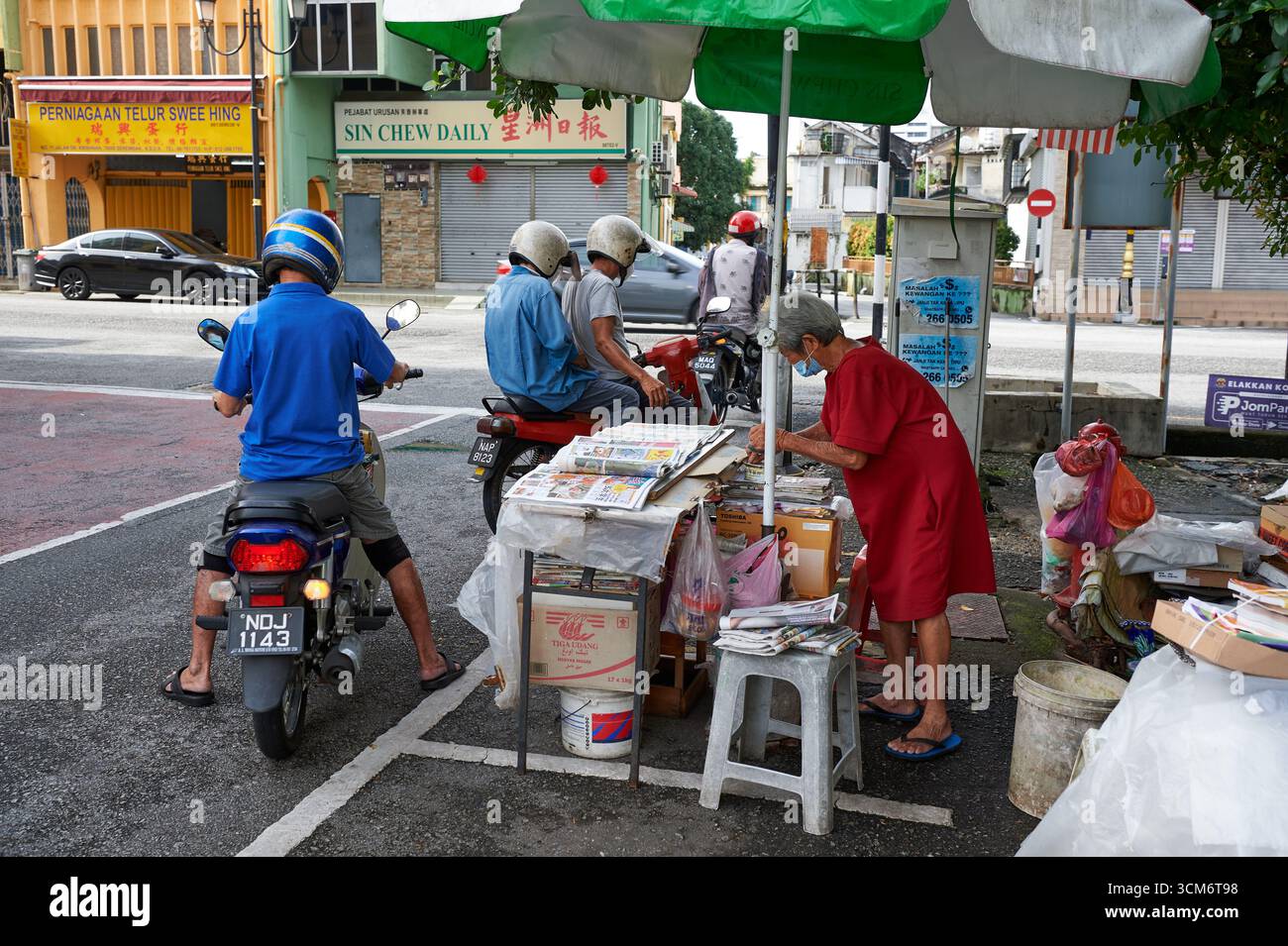 Old lady selling newspaper by the roadside in Seremban old town, Negeri ...