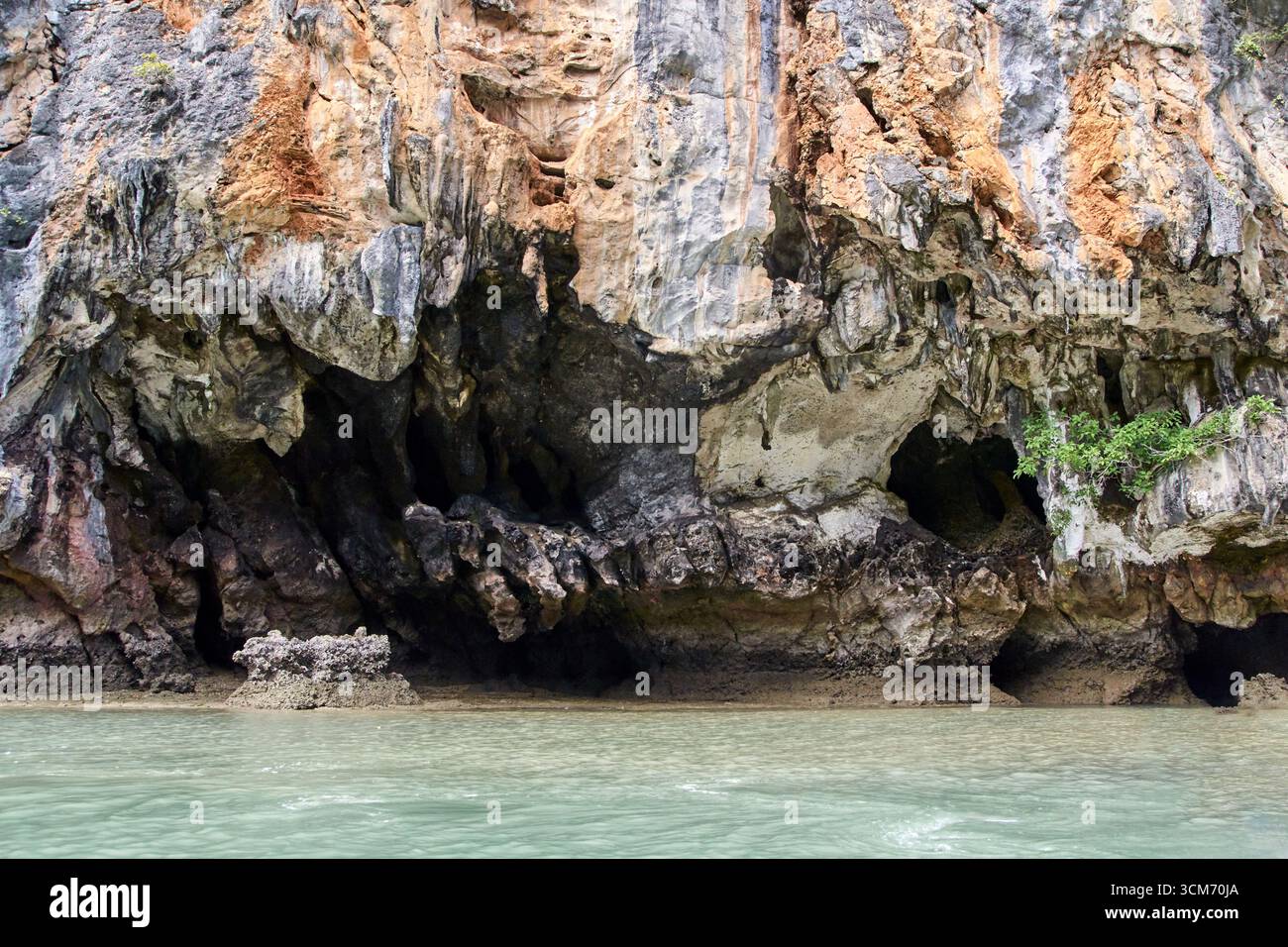 Limestone cliffs with natural caverns and green water at coastal ...