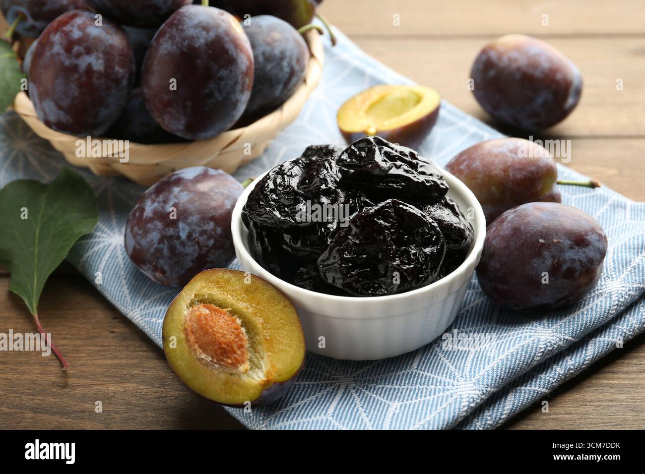 Dried prunes, fresh plums and green leaf on wooden table, closeup Stock ...
