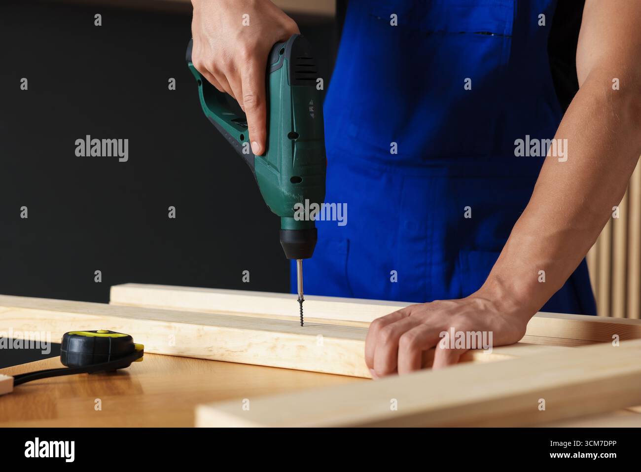 Professional repairman twisting screw into wooden plank with electric ...