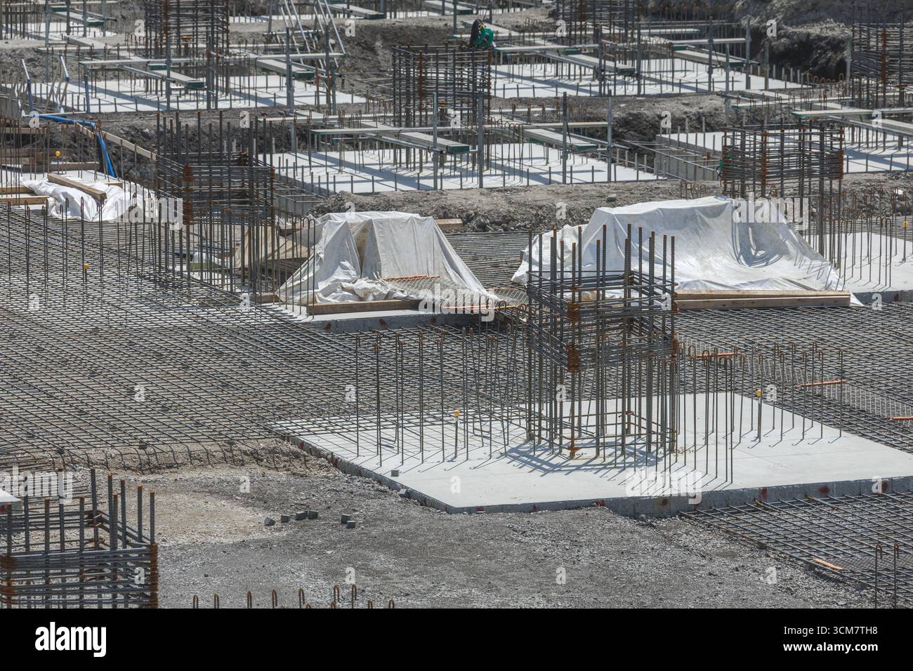Construction site displays multiple concrete foundations with steel ...