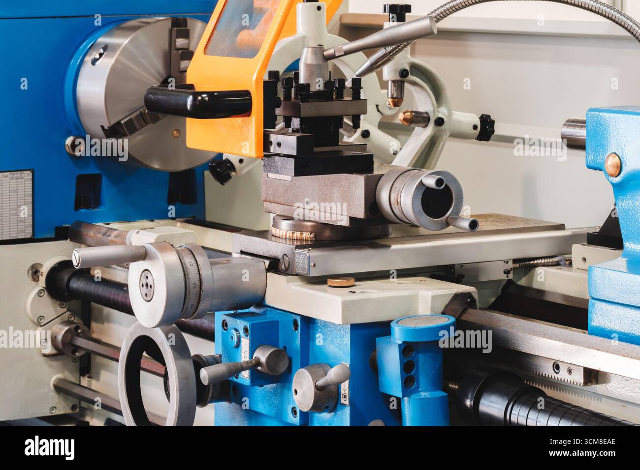 Blue and white lathe with black and orange part. The machine is ...