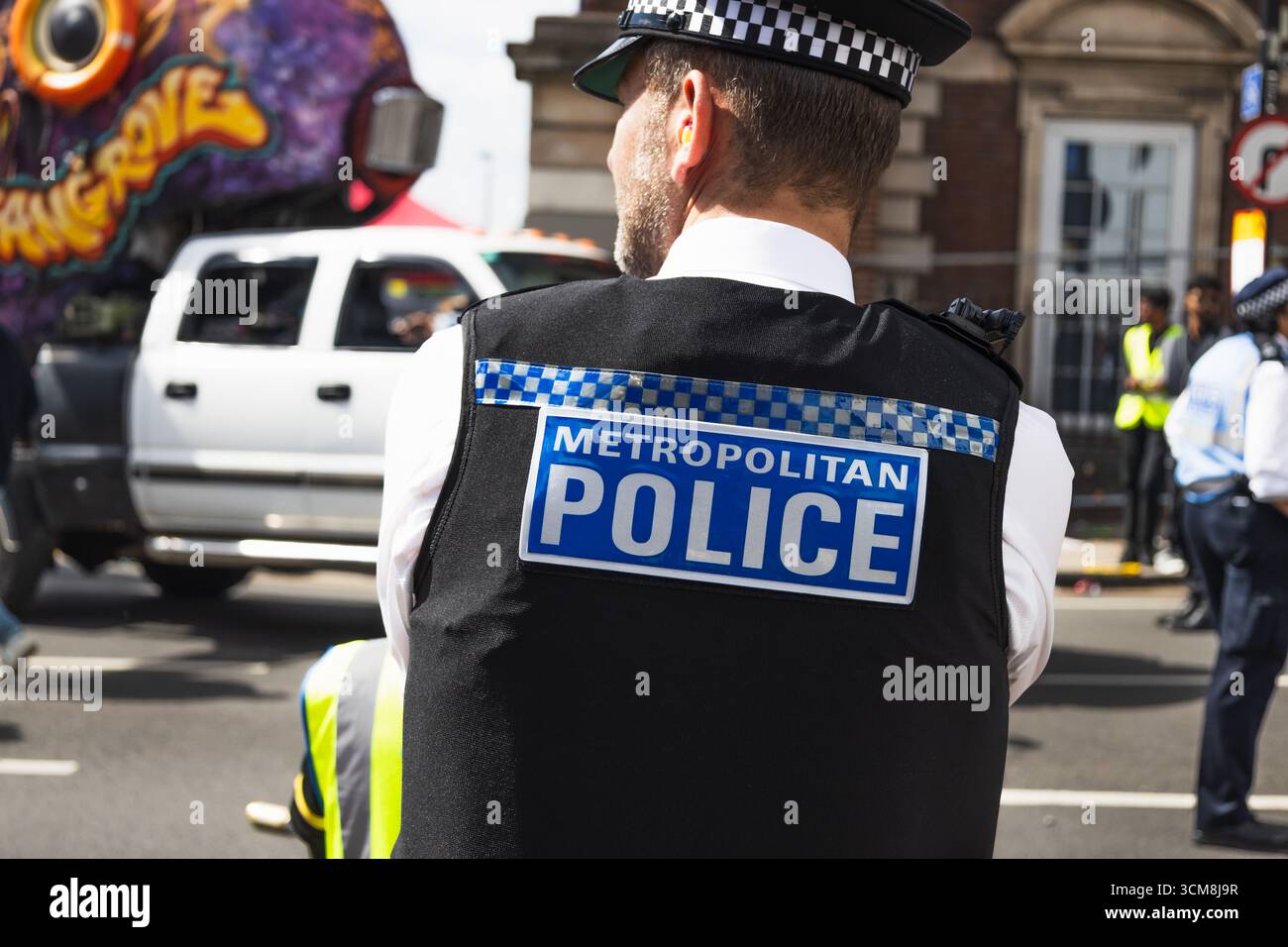 Uniformed UK police constable on duty in urban London, overseeing crowd ...