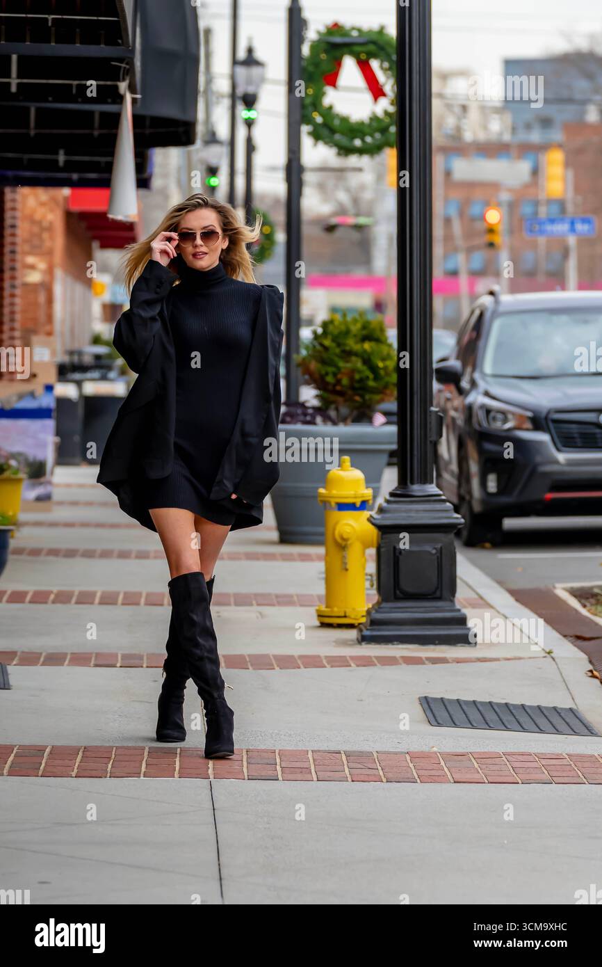 A beautiful young blonde woman strolls through a festive small town ...