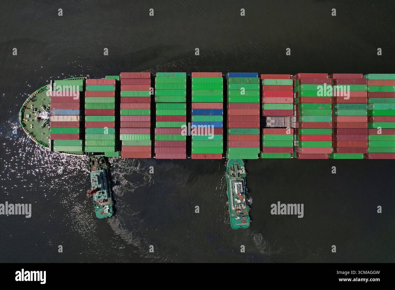 FILE - Tugboats assist a container ship as it prepares to dock at the ...