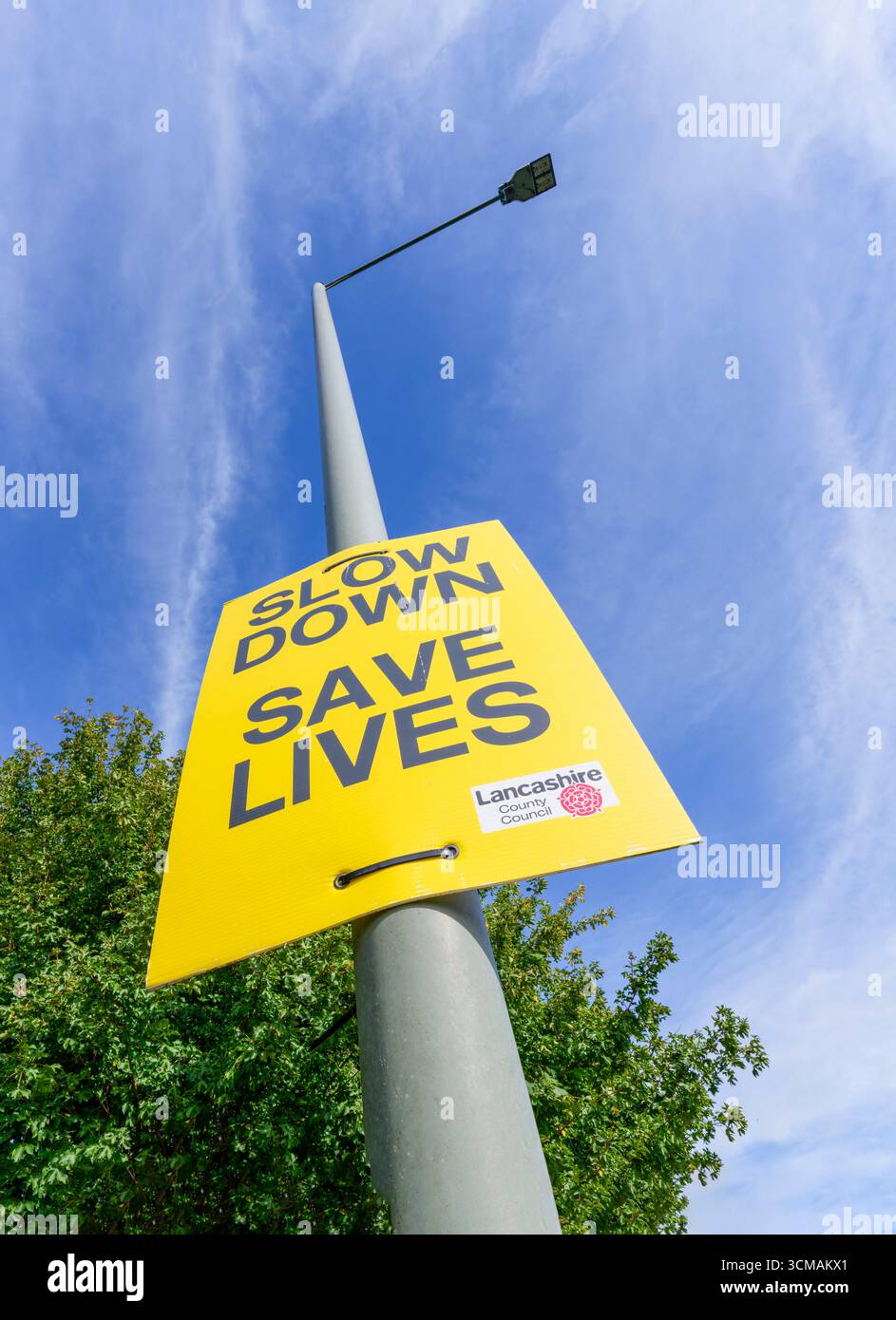 A British road sign, attached to a lamp post, asking drivers to slow ...
