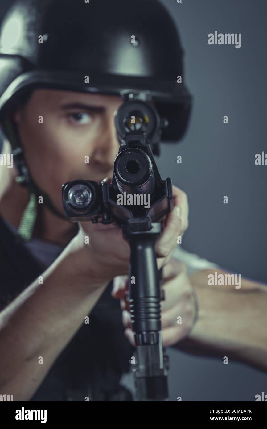 Warrior paintball sport player wearing protective helmet aiming pistol ...