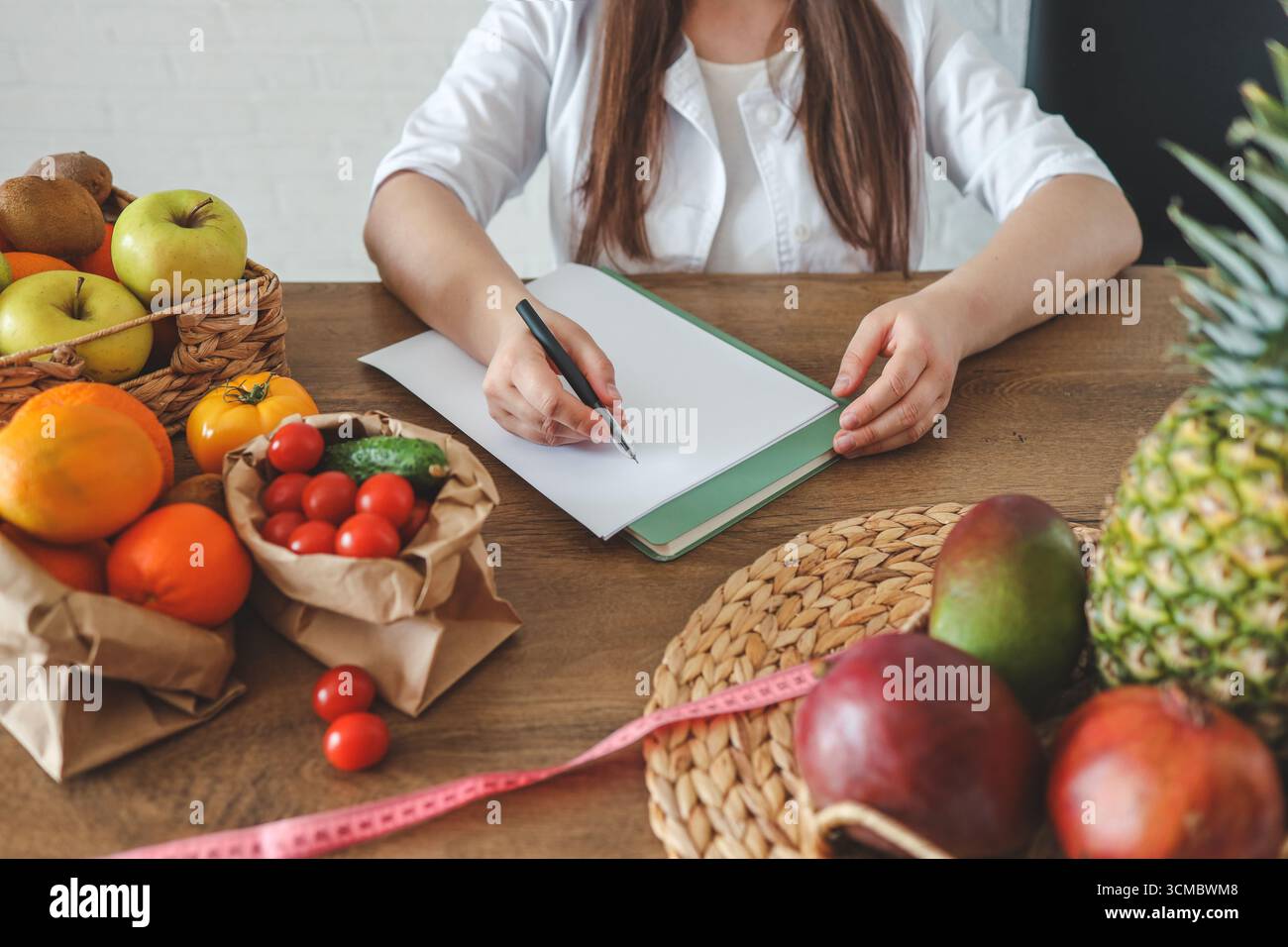 Doctor nutritionist writing case history in the office. Young woman ...