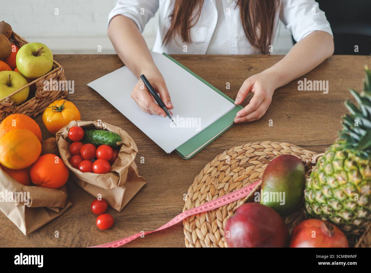 Doctor nutritionist writing case history in the office. Young woman ...