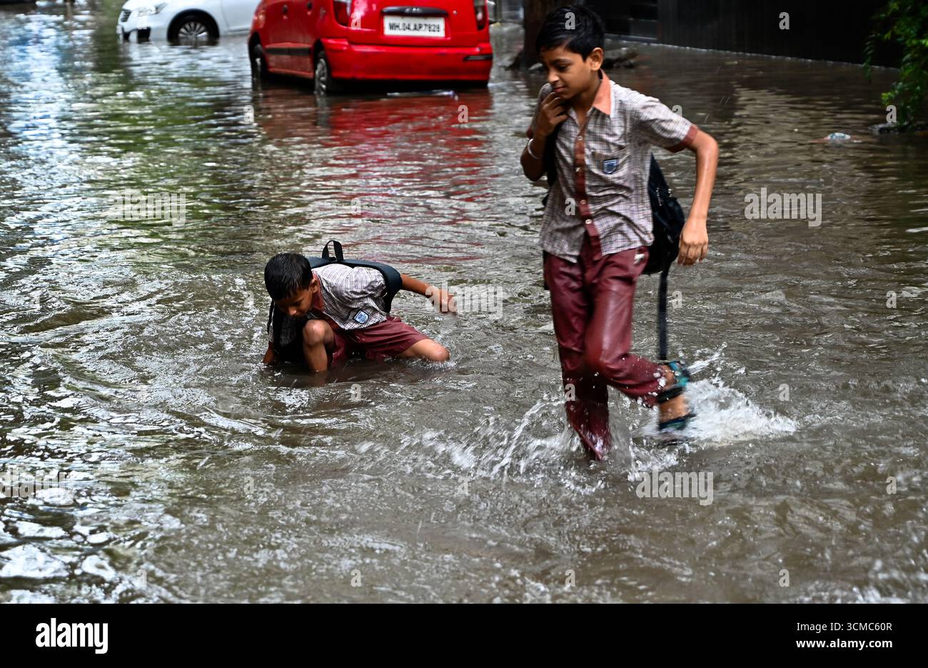 MUMBAI, INDIA - SEPTEMBER 15: School Children wade through waterlogged road at Matunga after ...