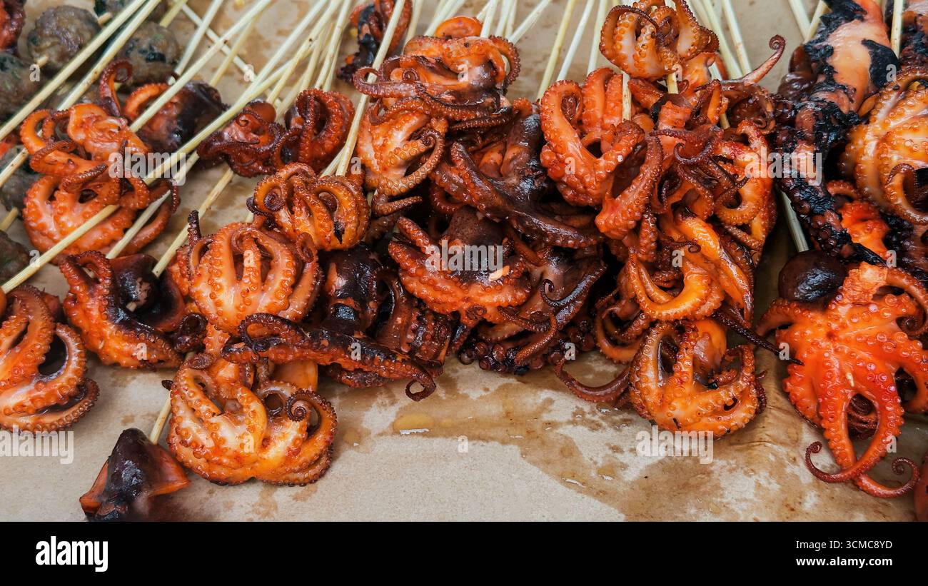 Grilled octopus skewers with curled tentacles displayed as traditional ...