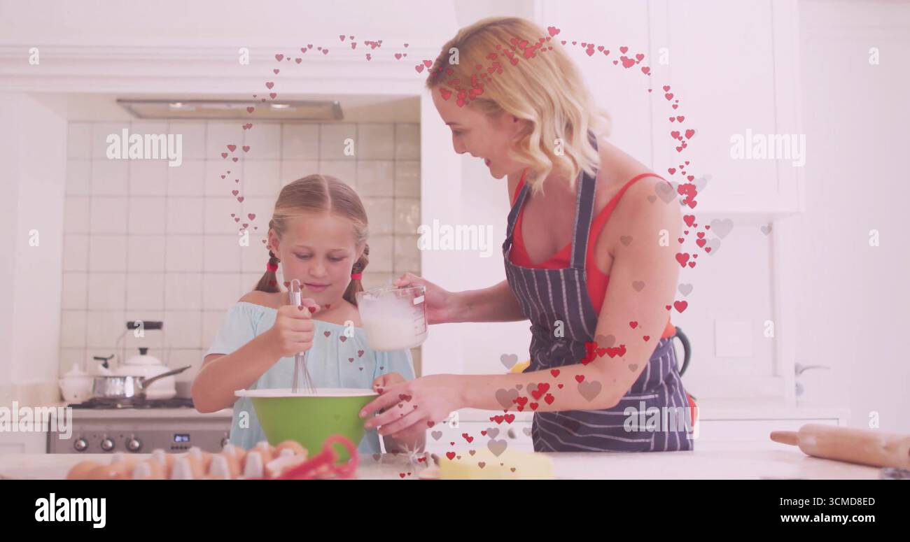 Mother in apron stirring batter and pouring milk with daughter at white ...