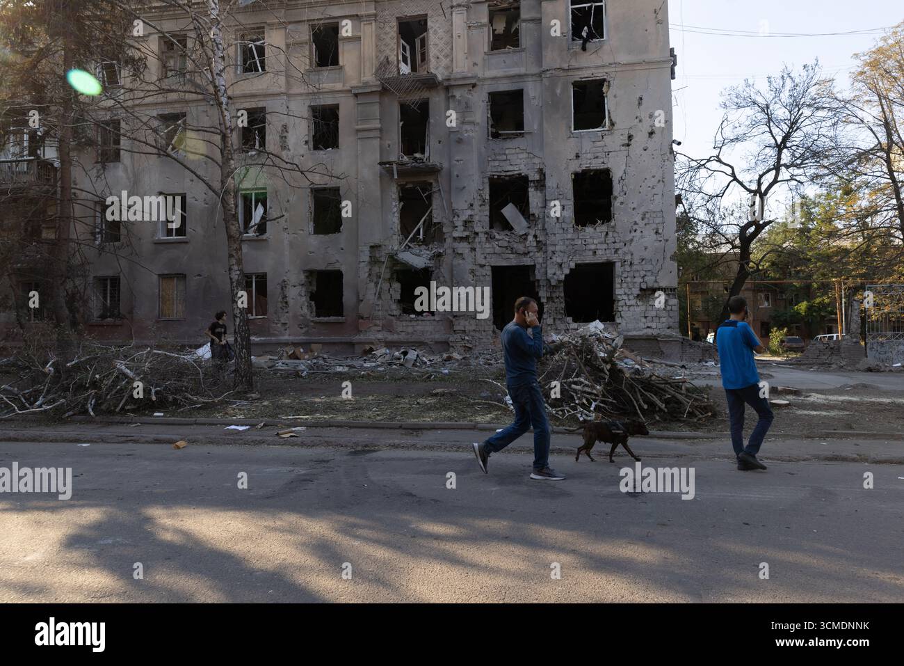 People walk among damaged residential buildings after a Russian strike ...