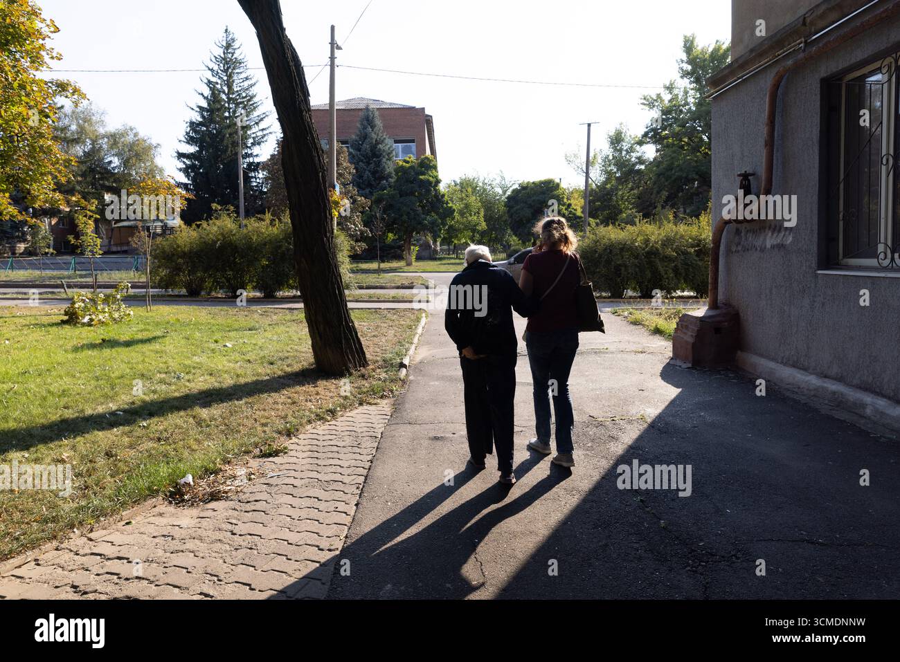 People walk among damaged residential buildings after a Russian strike ...