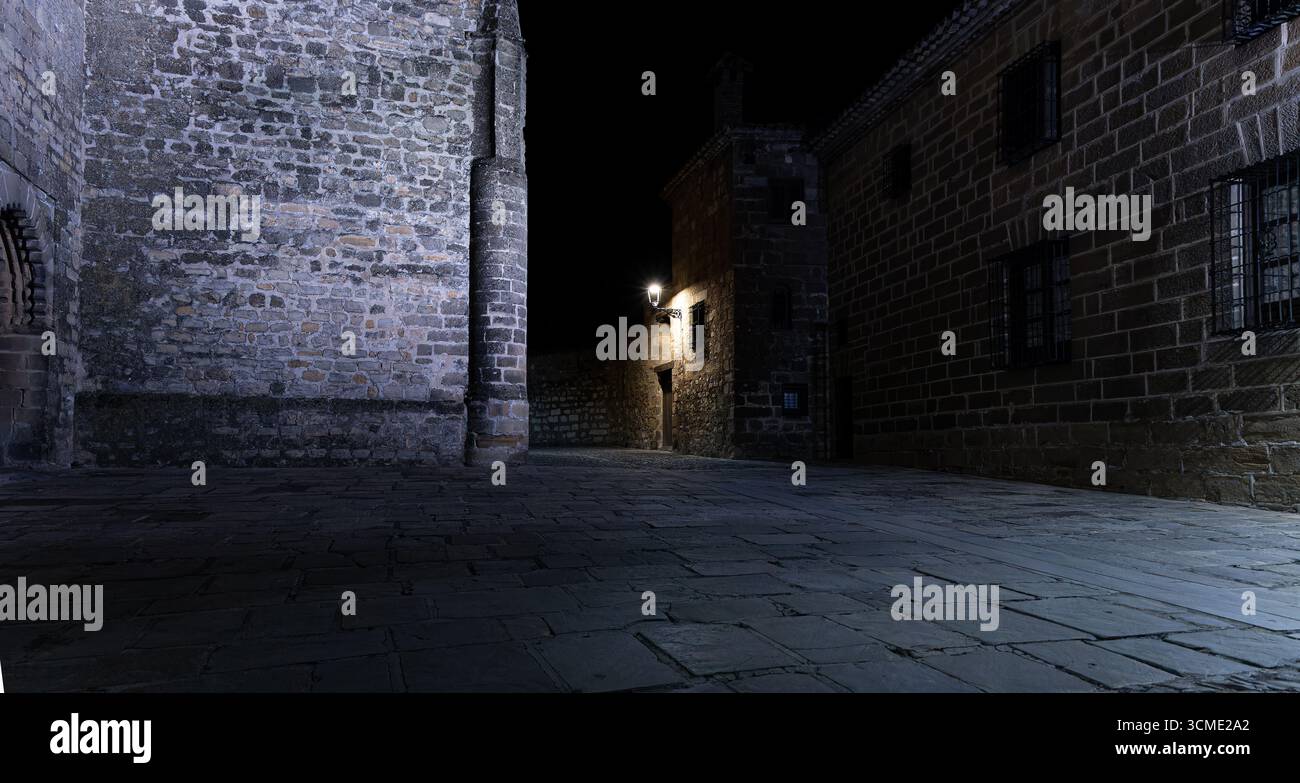 A dark alleyway of a medieval town with a street lamp shining on a ...