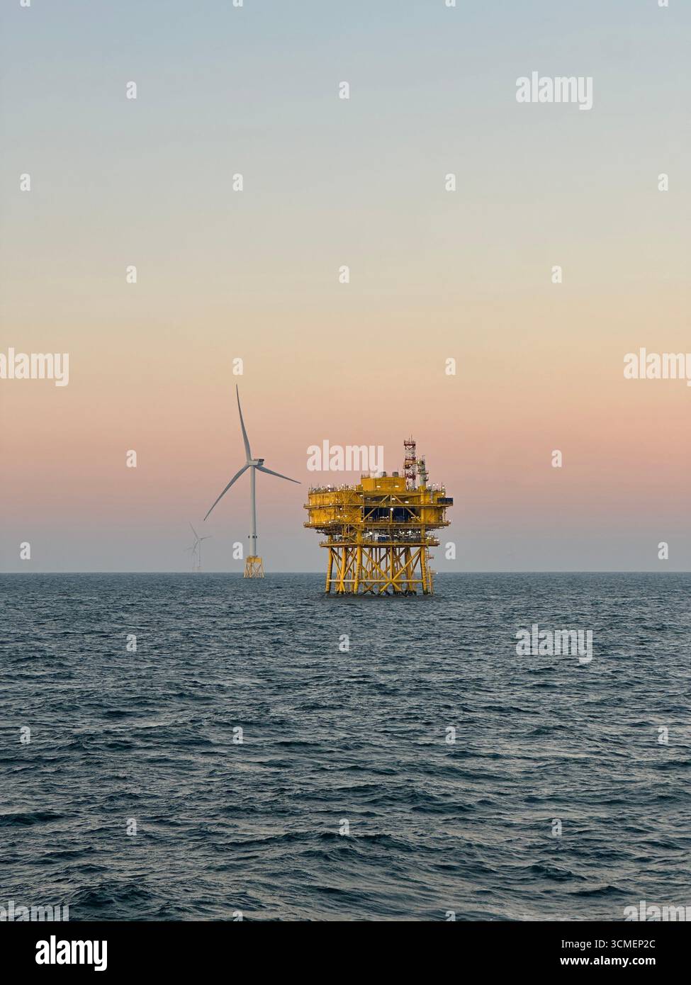 Offshore wind farm substation platform with turbine in background ...