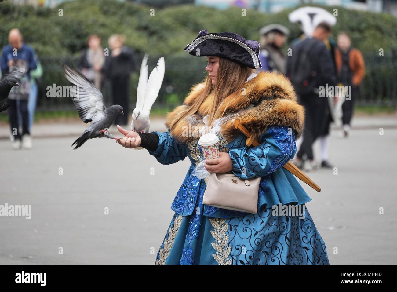 A street performer wearing a 18th century costume feeds pigeons in St ...