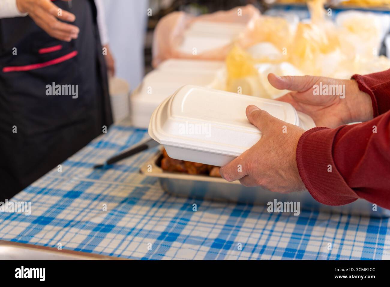 Hands exchanging takeout container at outdoor cafe. Customer picking up ...