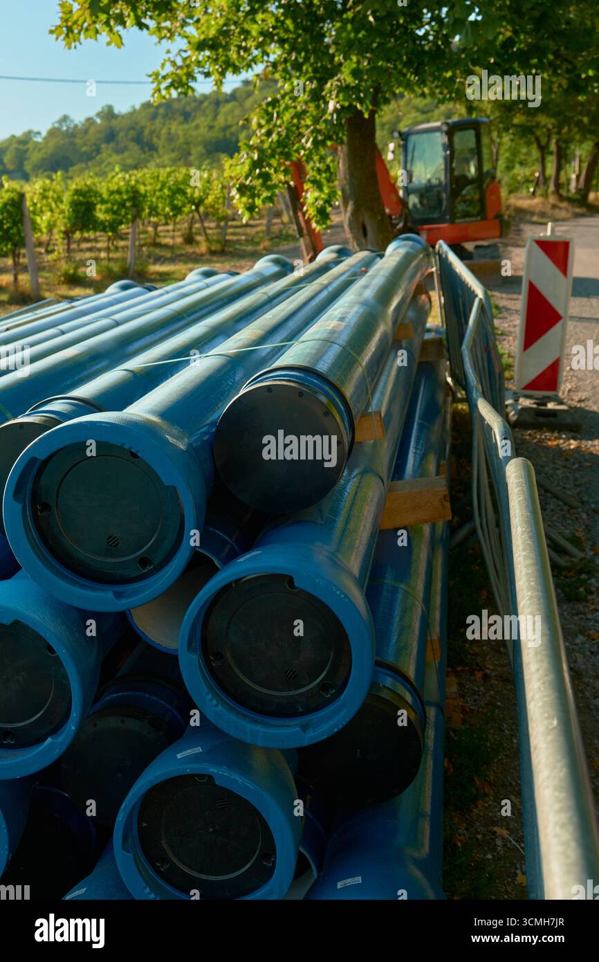 Vertical photo of neatly stacked blue industrial pipes and tubes by a ...