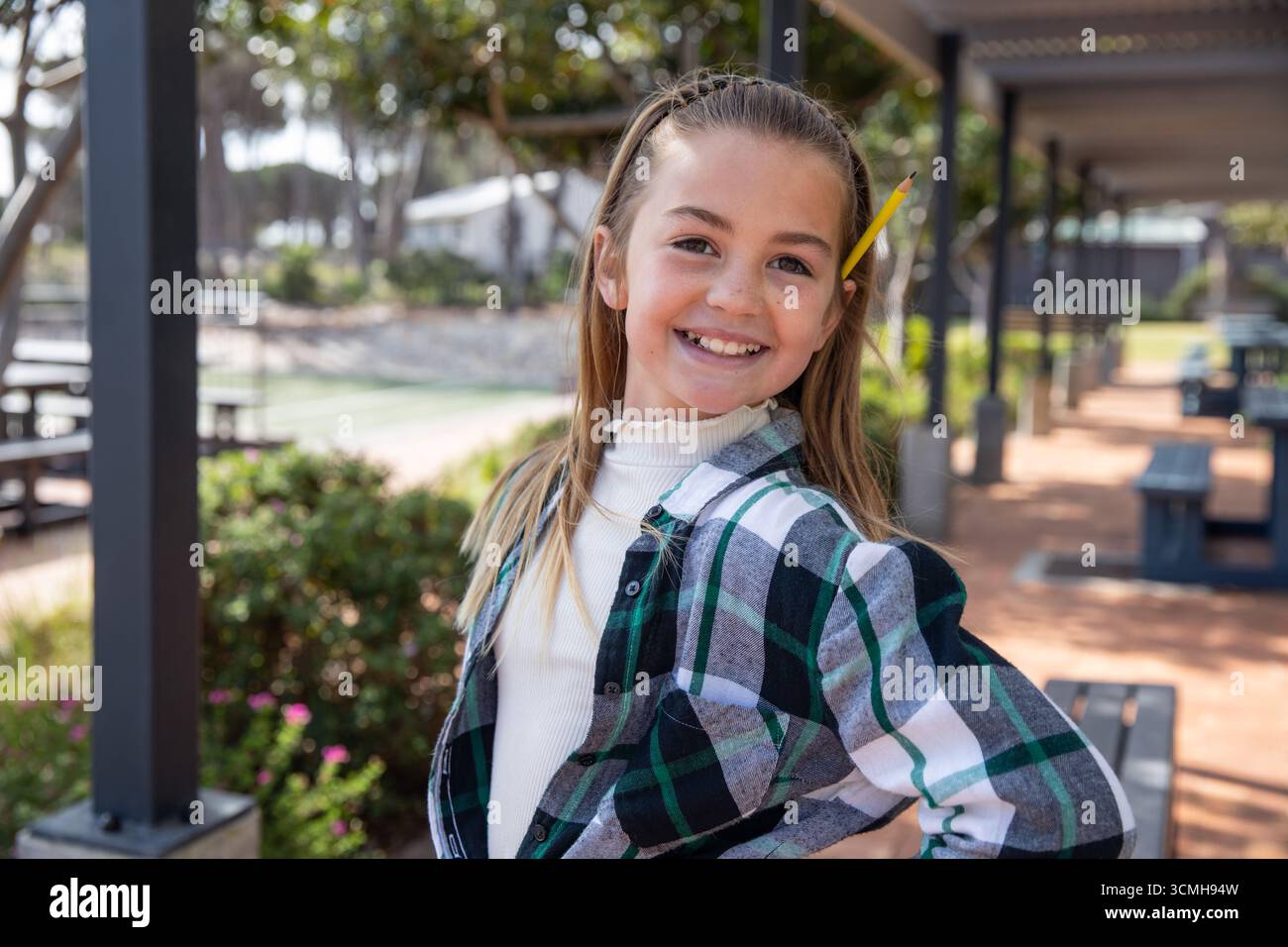 Elementary school girl standing and smiling on courtyard walkway with ...