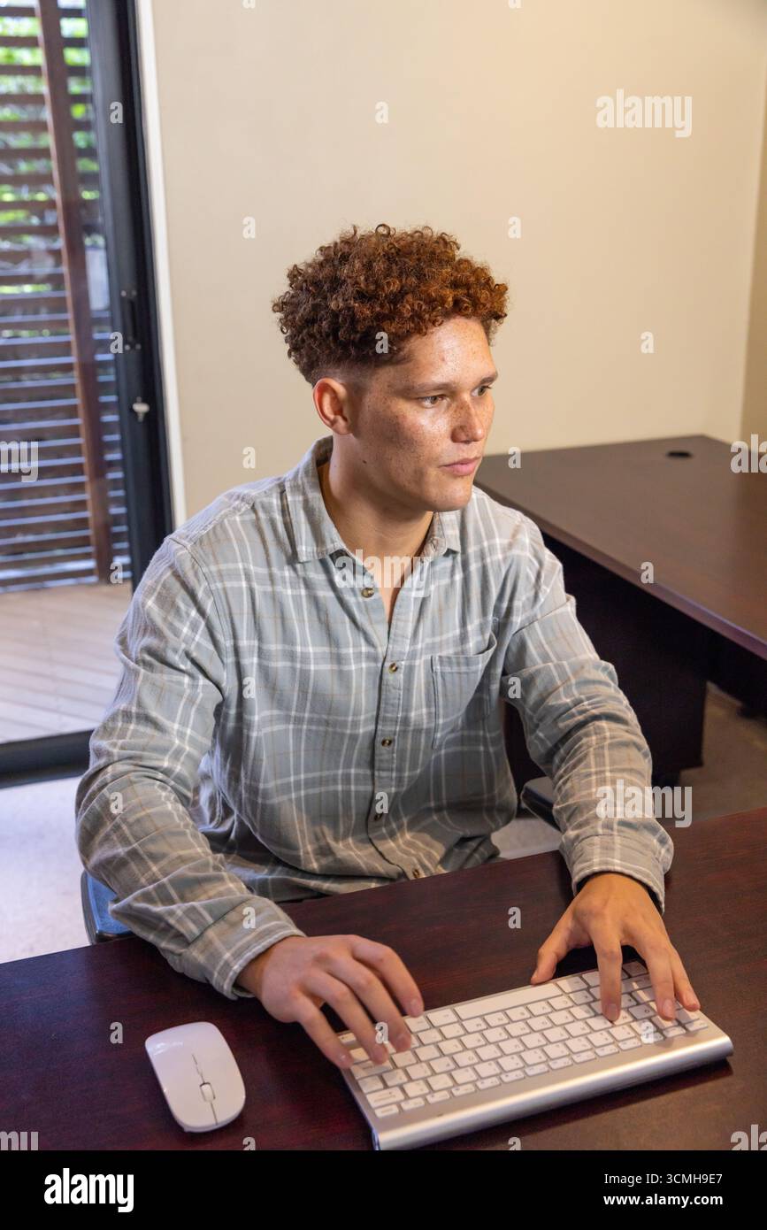 Adult male typing on wireless keyboard at wooden desk by sliding glass ...