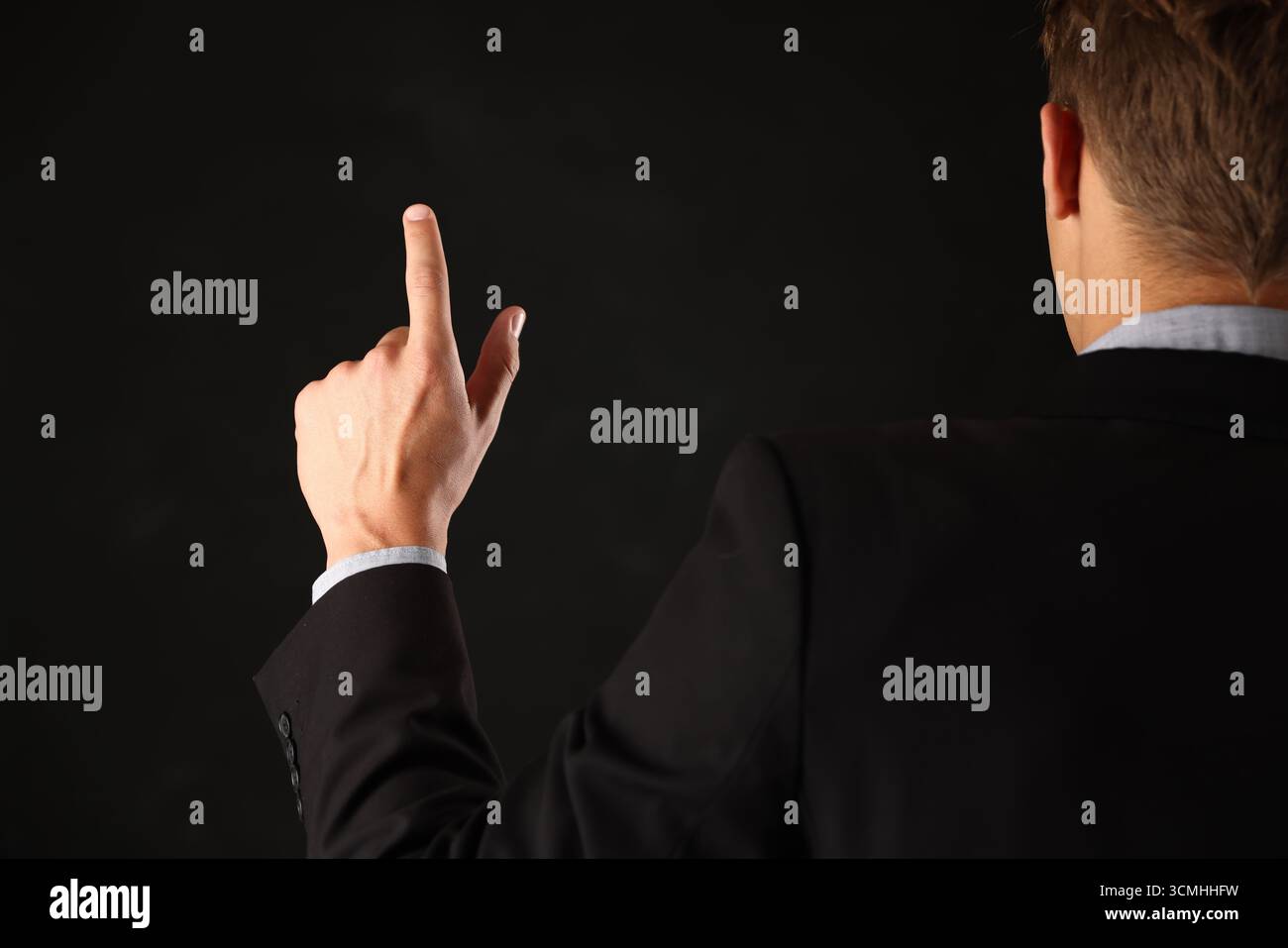 Man touching something on black background, back view Stock Photo - Alamy
