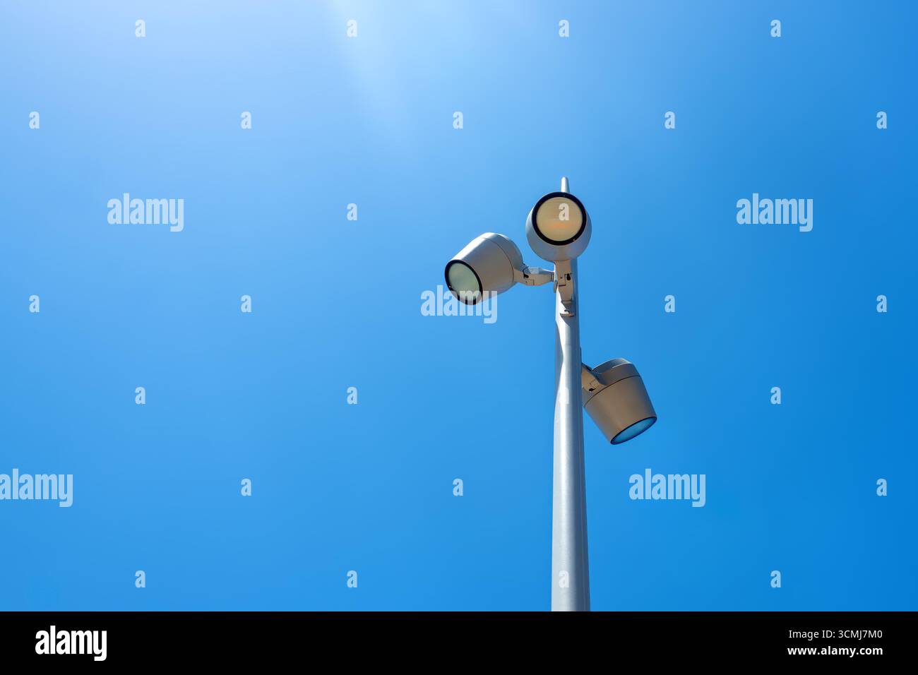 Minimalist modern street light with three lamps against bright blue sky ...