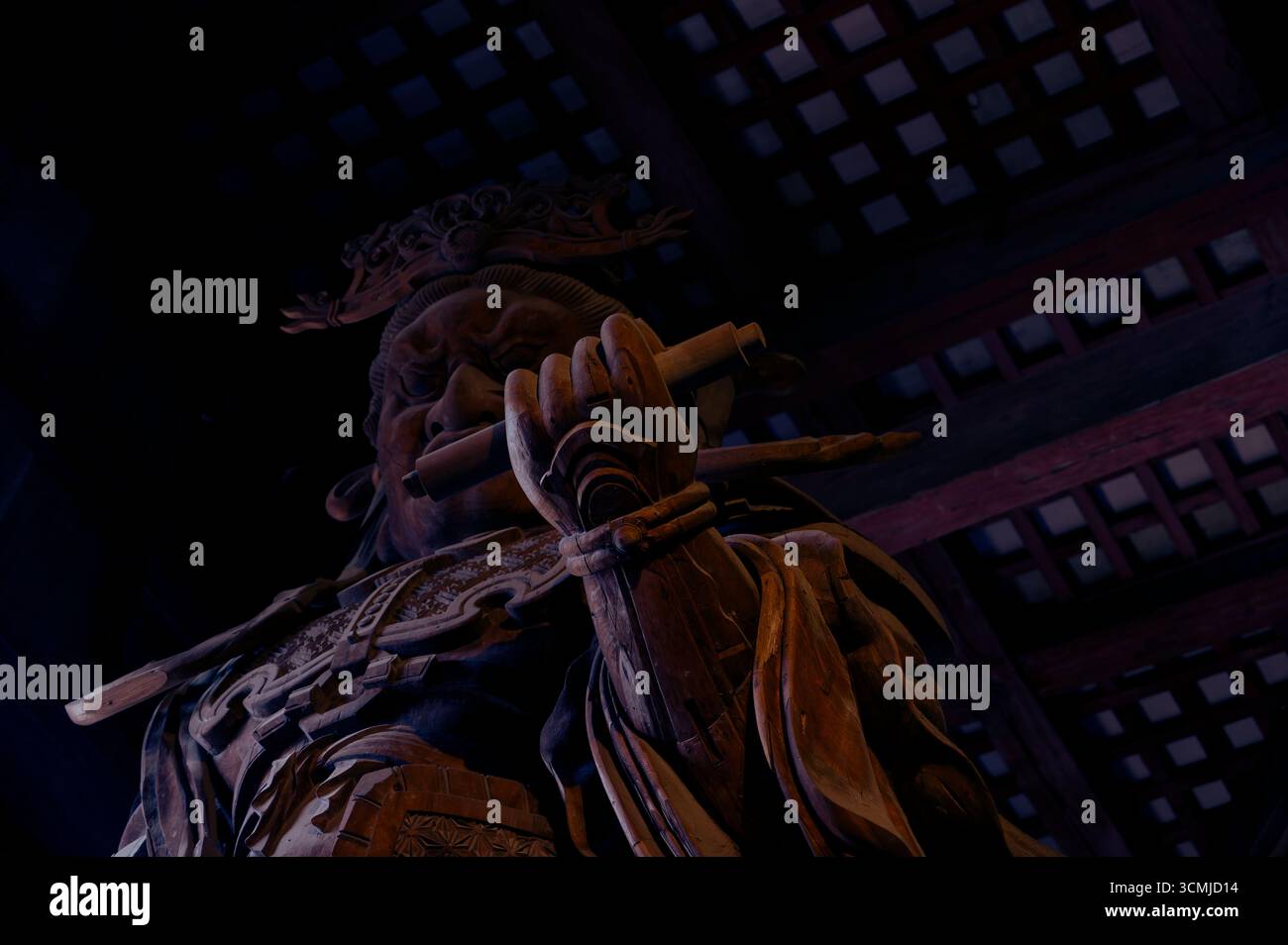 Wooden guardian statue cast in shadow inside the Great Buddha Hall of ...