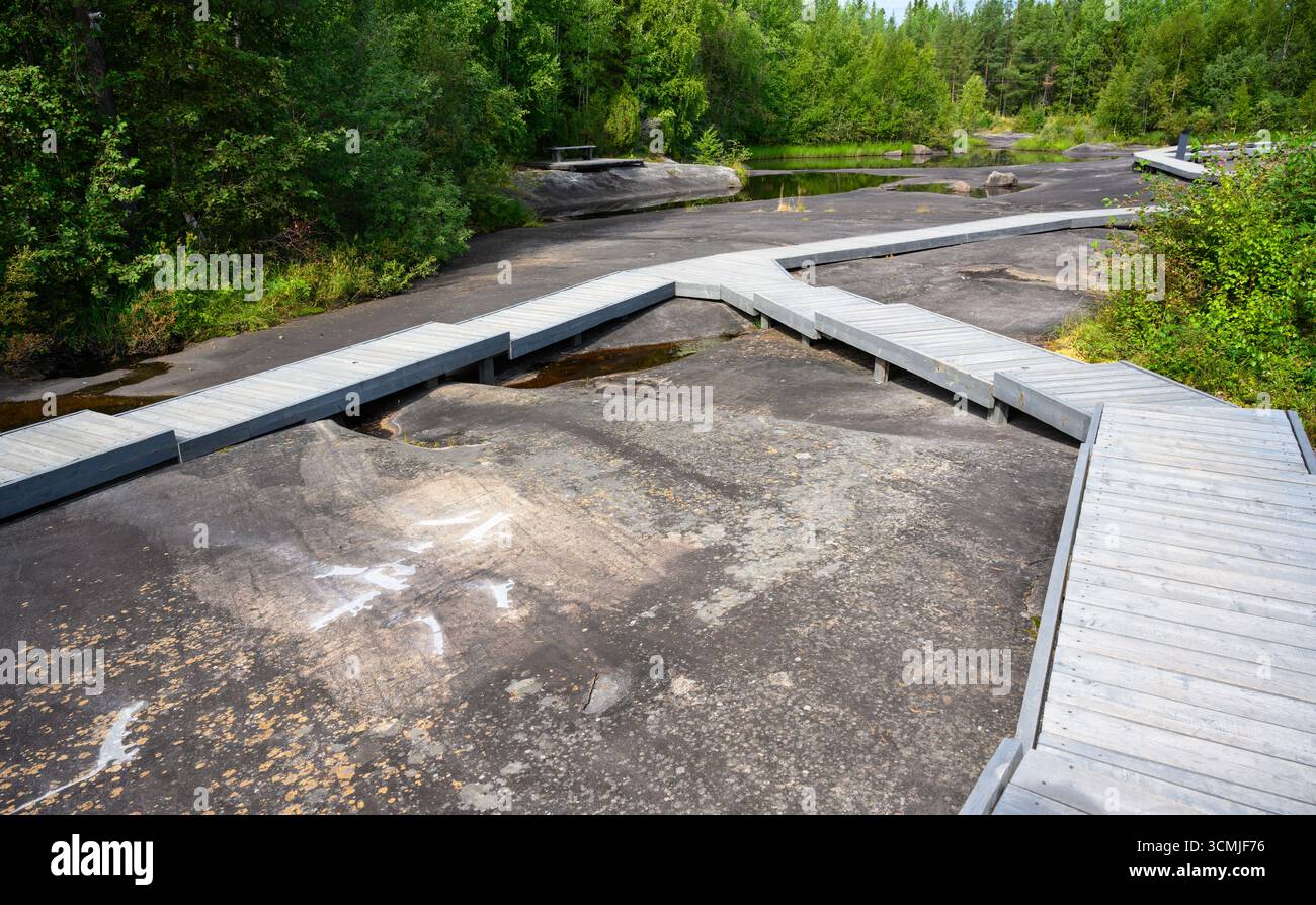 Wooden walkway over rock surface with prehistoric art in forest ...