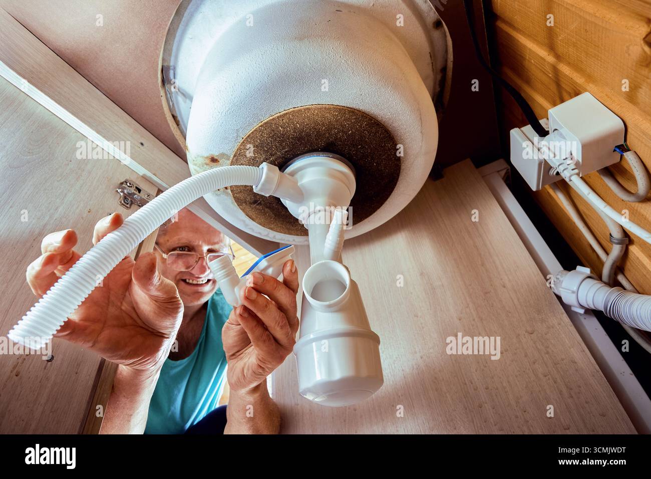 Pipefitter installs overflow under kitchen sink connecting flexible ...