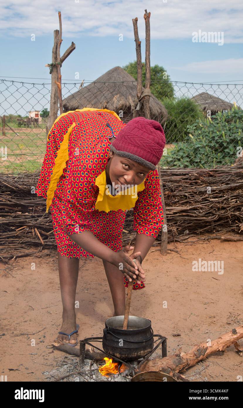 village african woman , cooking in a cauldron outdoors, wearing ...