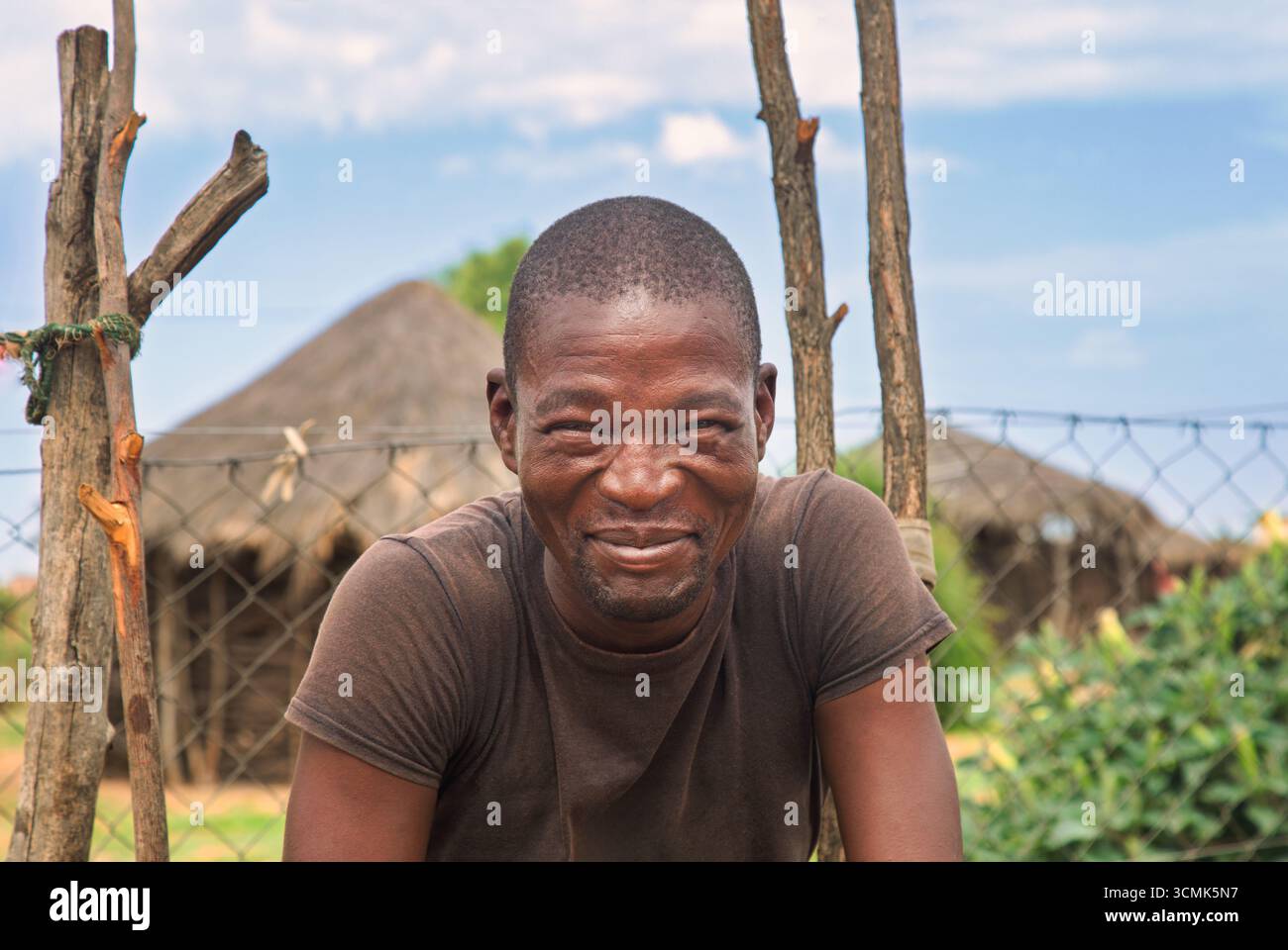 african village single smiling young african man, sitting in front of ...