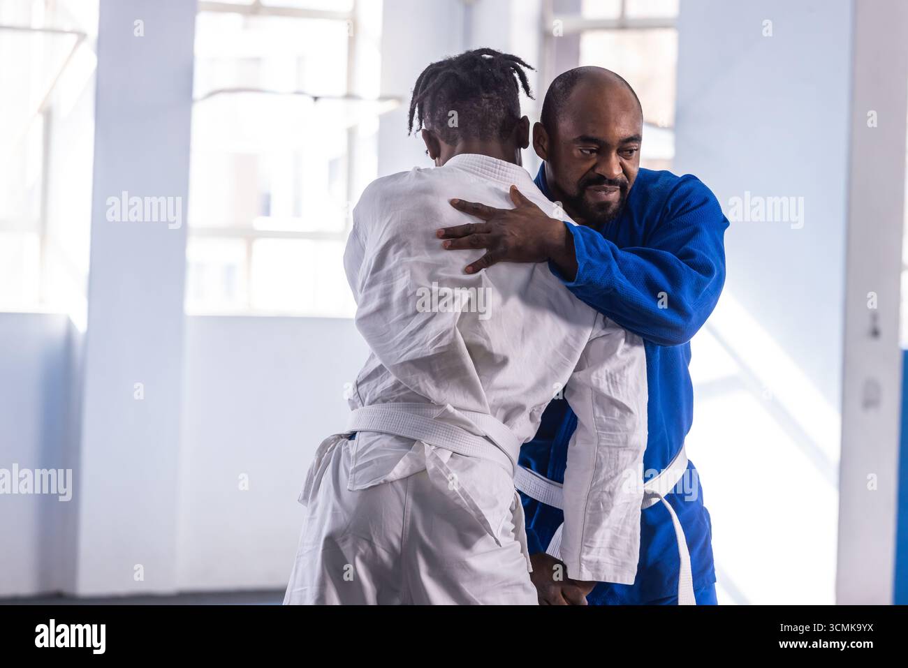 Adult african american men in blue gi gripping white gi, practicing ...