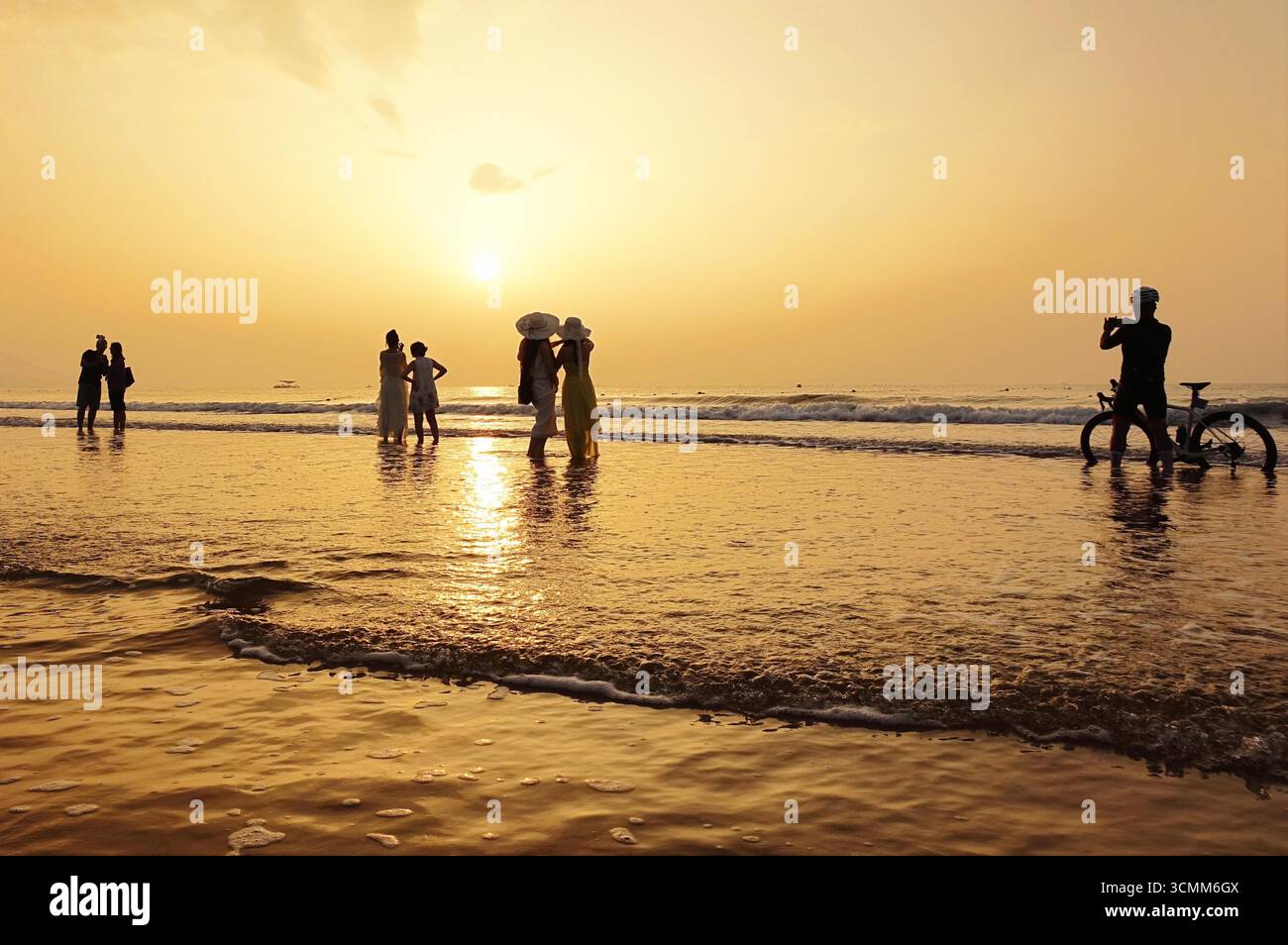 Tourists watch the sunrise at the golden beach in Qingdao City, east ...